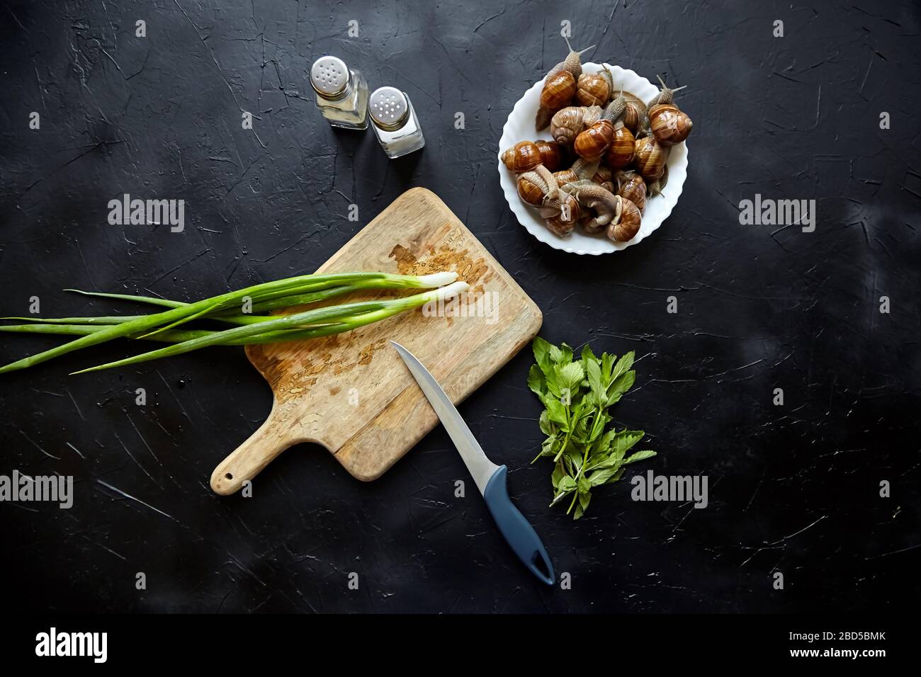 Cooking garden snails. Wooden cutting board and ingredients. Fresh mint ...