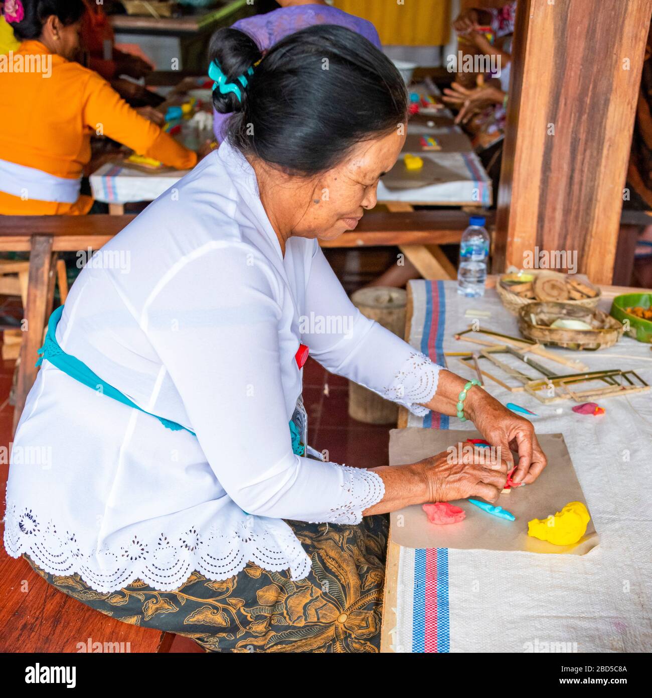 Square portrait of a lady making religious decorations with rice paste ...