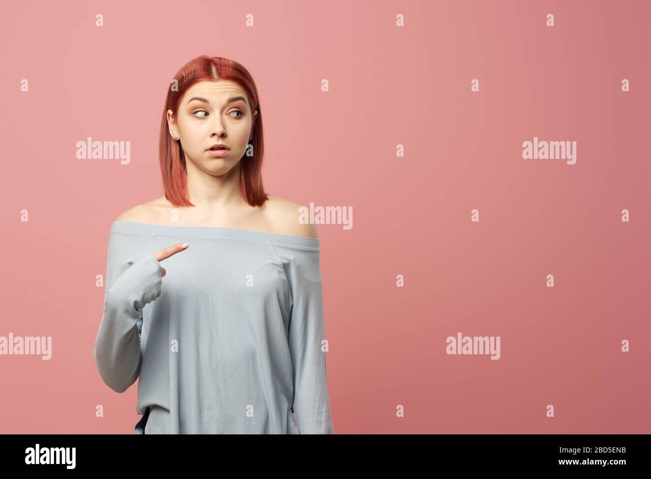 Serious ginger woman pointing finger to side standing in studio Stock ...