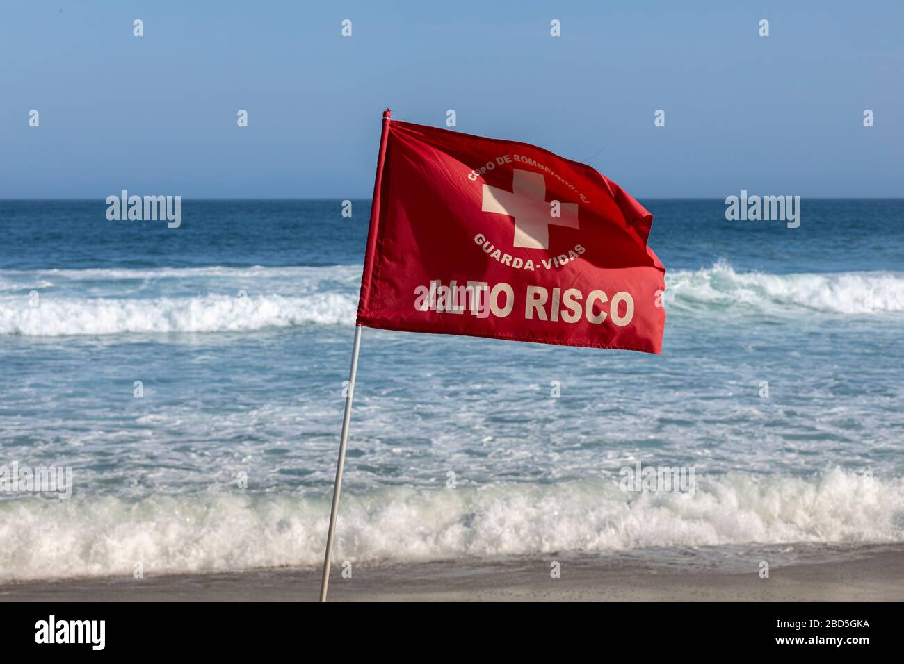 Red warning flag on Leblon beach with waves coming in in the background ...