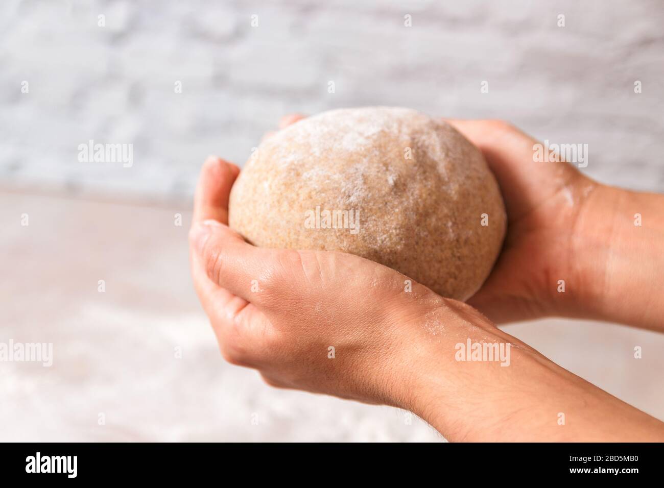 closeup woman hands holding kneaded dough from rye flour over marble ...