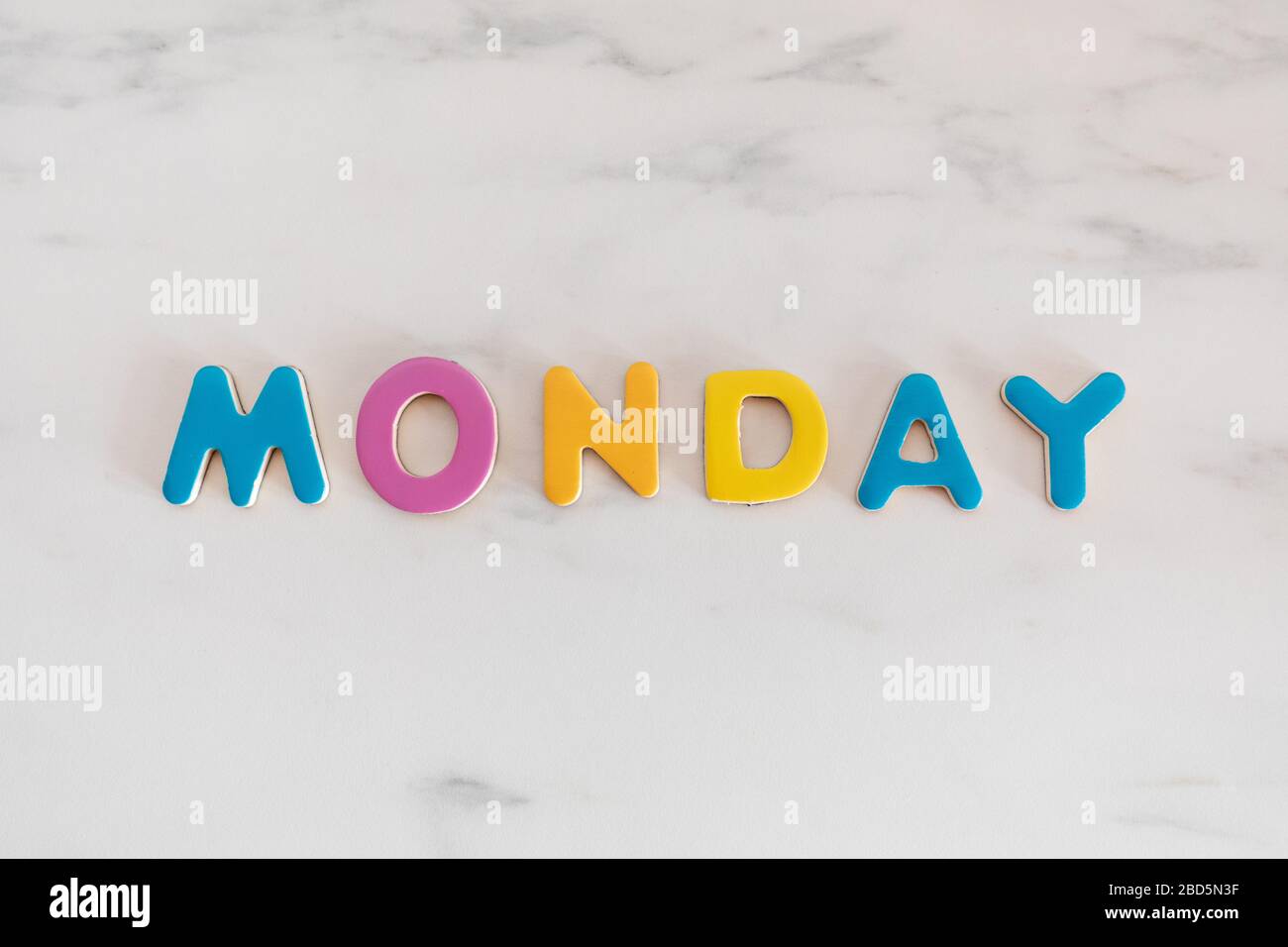 Monday word written with colorful letters on white marble stone ...