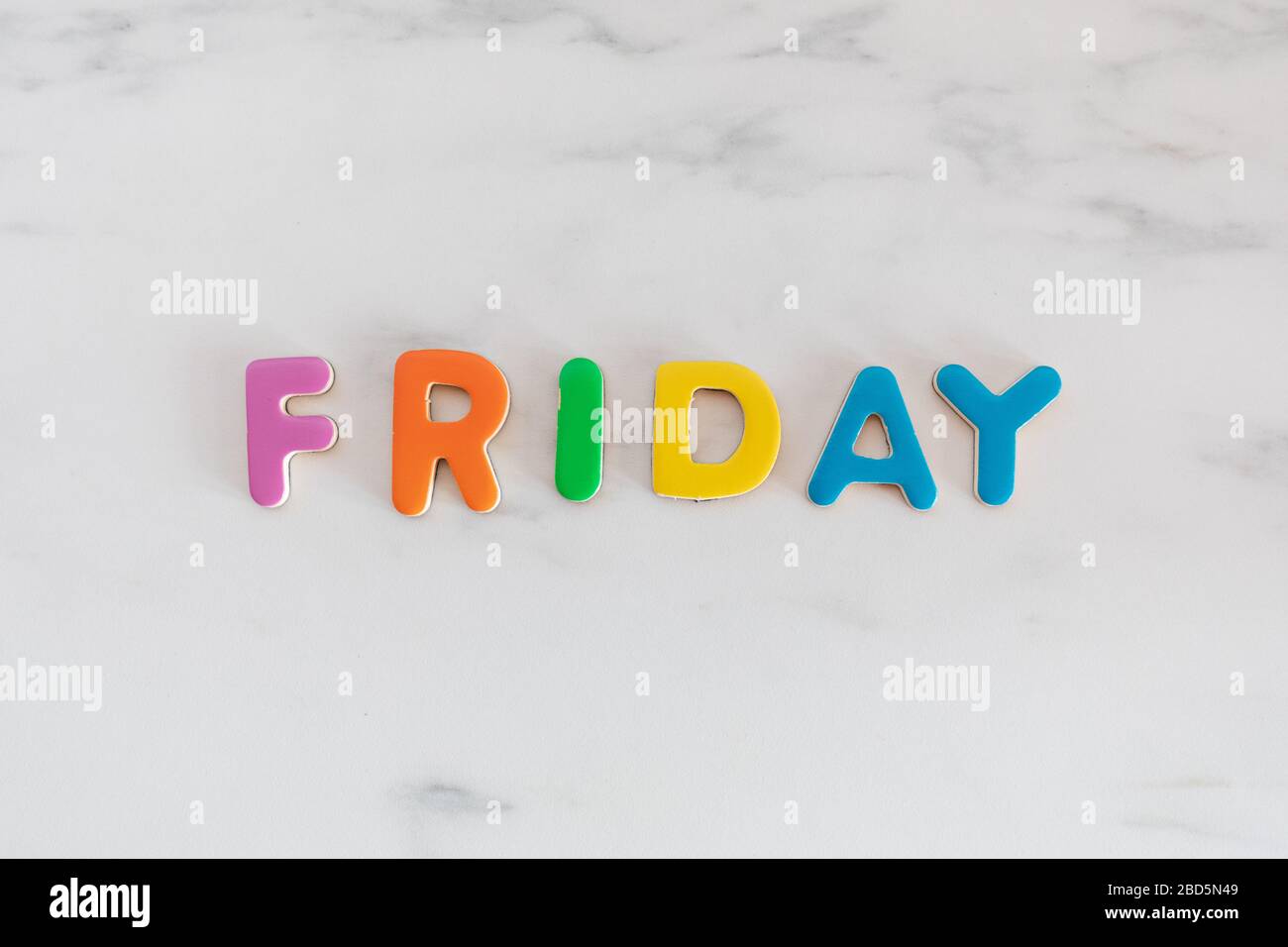 Friday word written with colorful letters on white marble stone ...