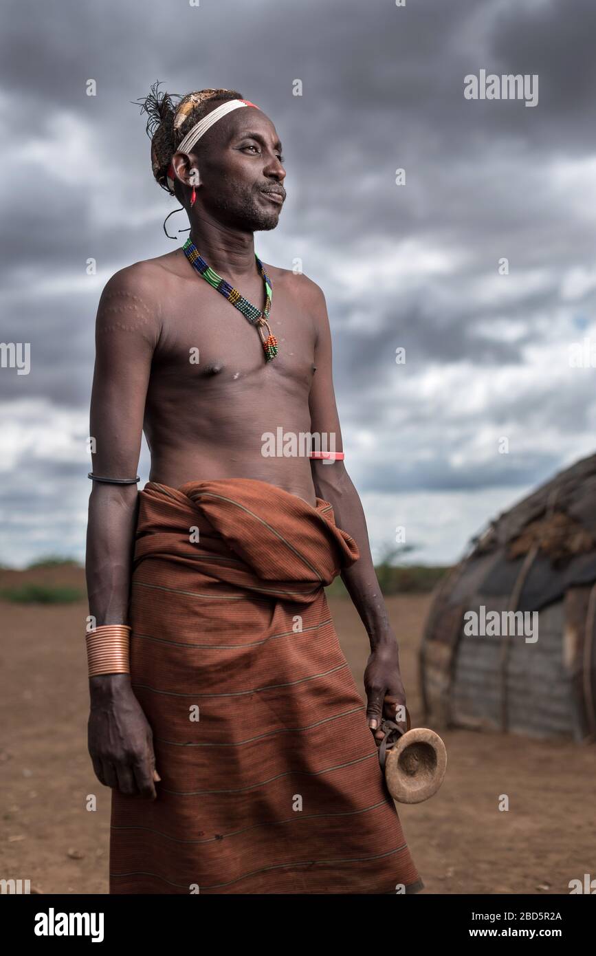 A male member of the Dassanetch ethnic group or tribe poses holding his ...