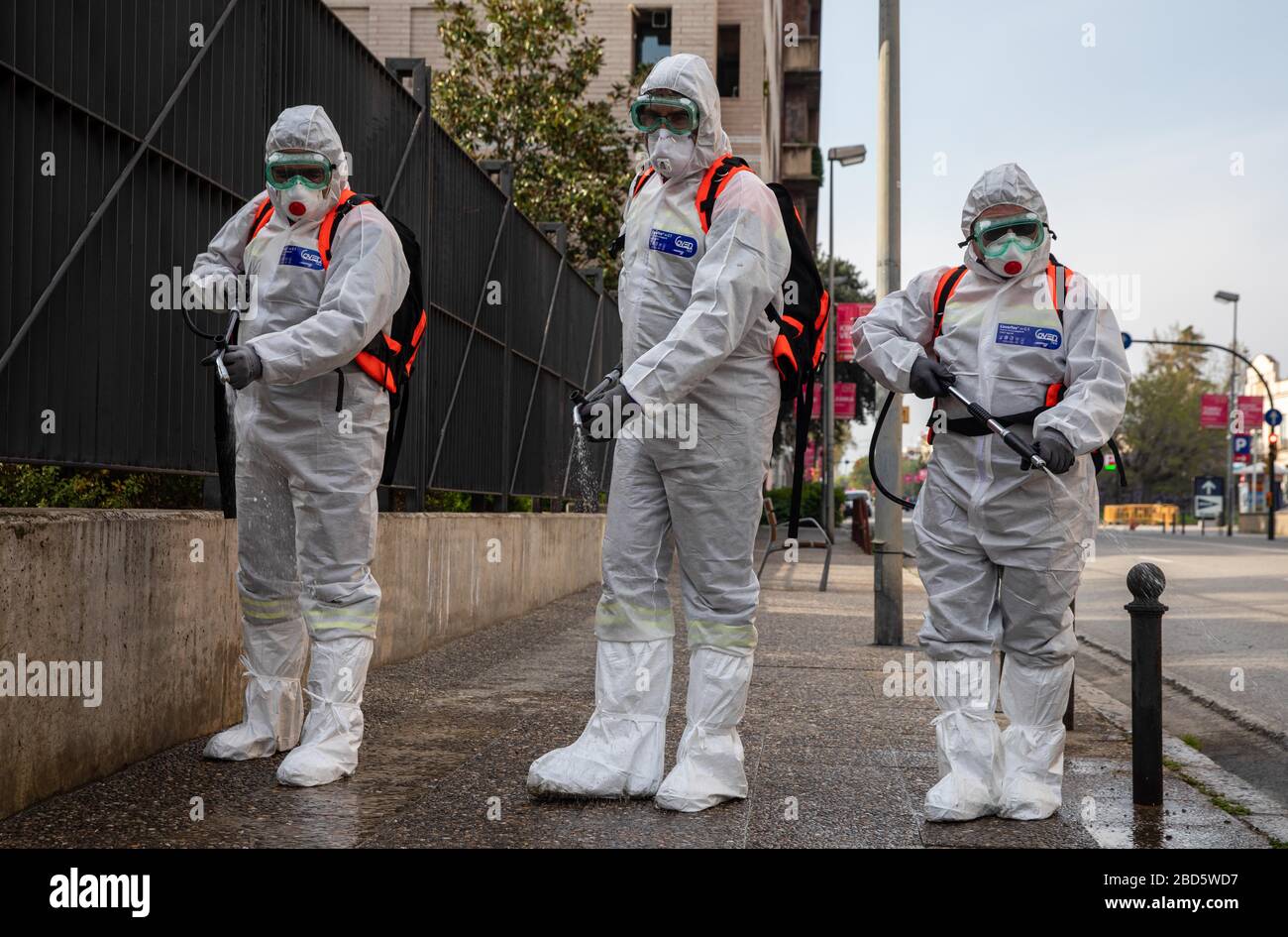 Civil protection agents dressed in protective suits spray disinfectants ...