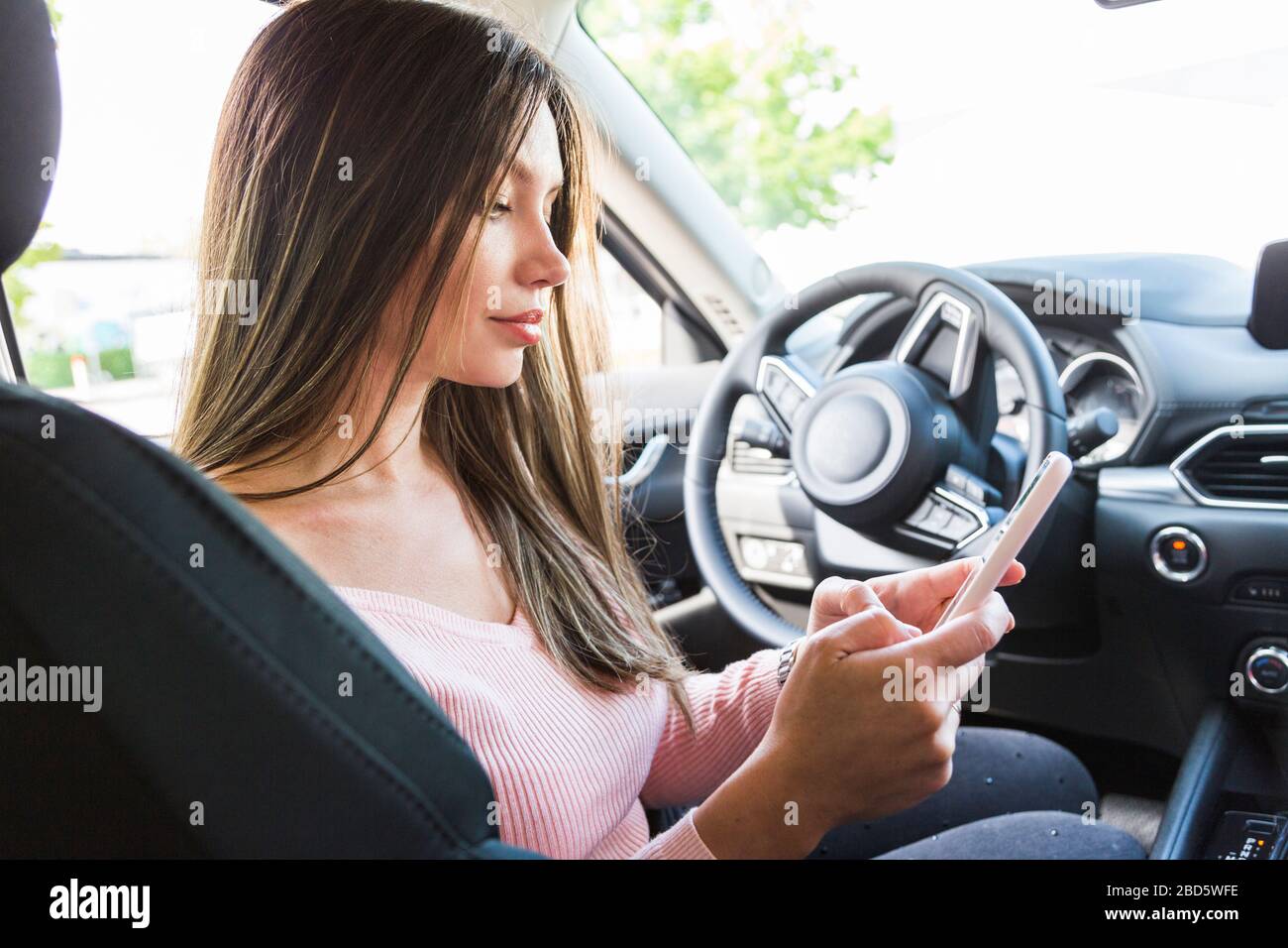 Girl driver sits behind steering wheel with mobile Stock Photo - Alamy