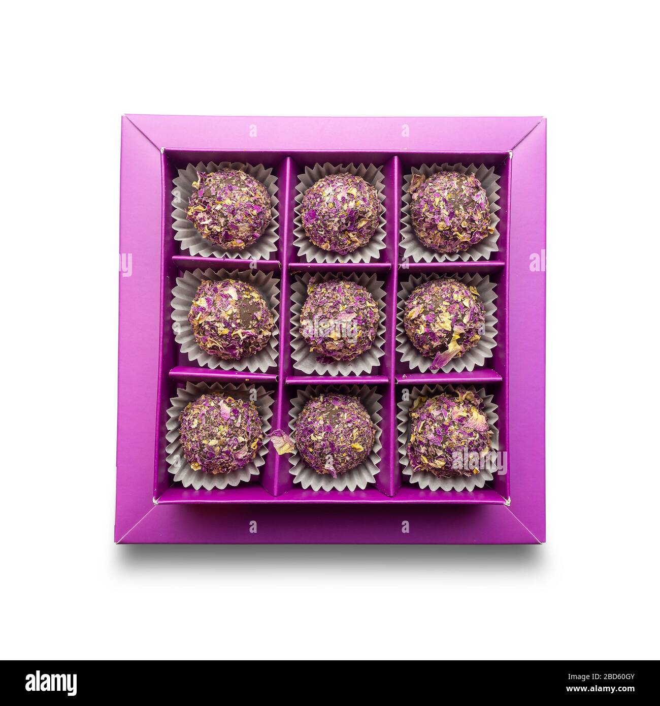 Top view of purple box with round sweets sprinkled with dry rose petals ...
