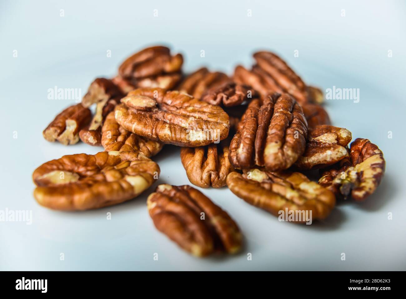 Walnuts of Pecan on white cutting board Stock Photo - Alamy