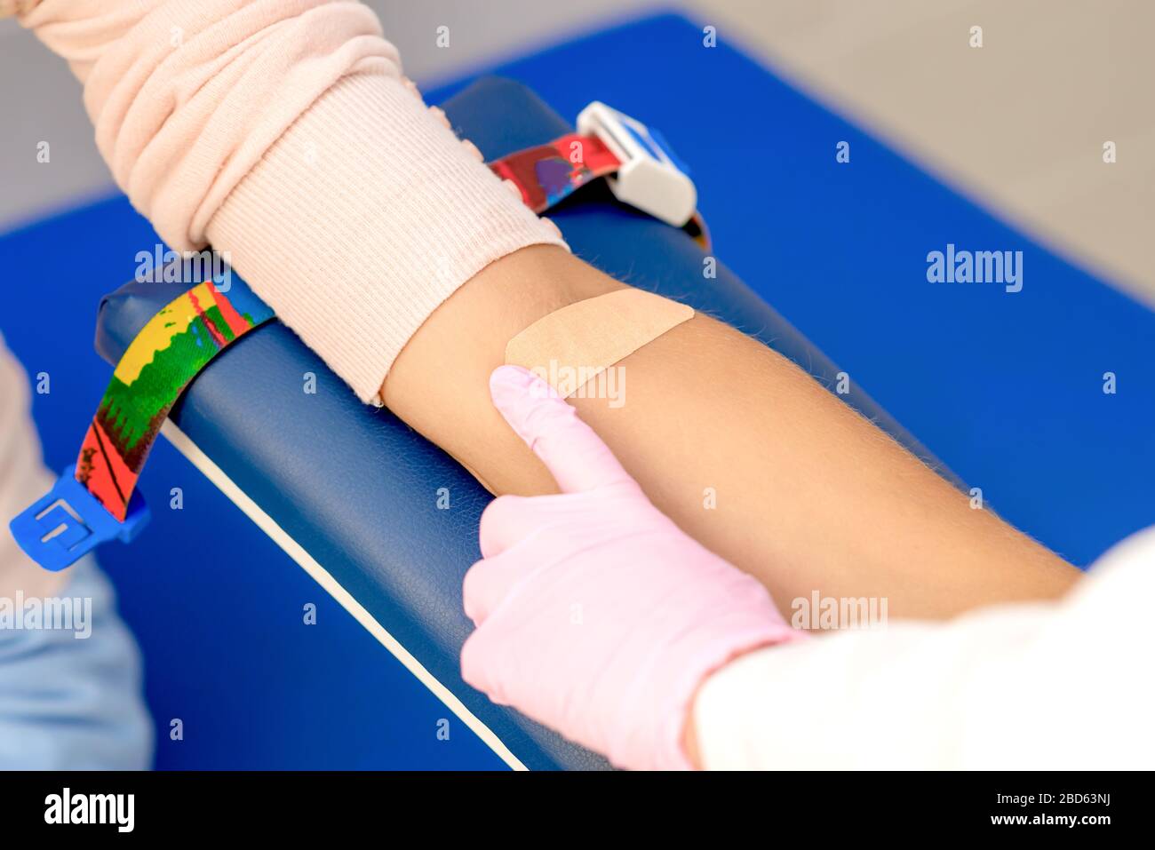 Doctor in rubber protective gloves glues an adhesive plaster on arm ...