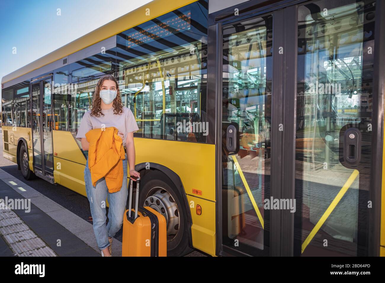 Portrait of a teenage girl at the bus station with a medical face mask ...