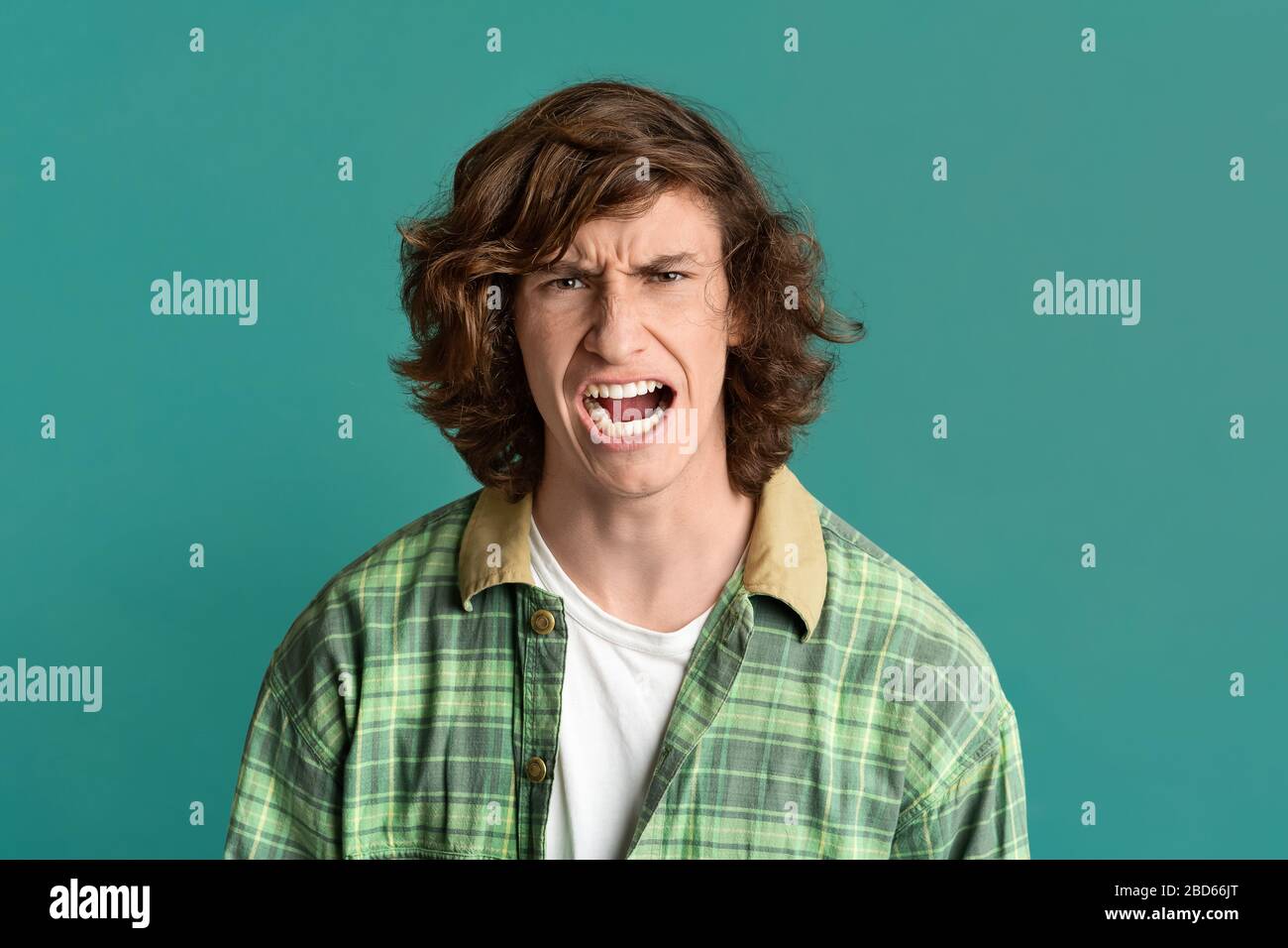 Expressing anger. Young guy with furious facial expression on color ...