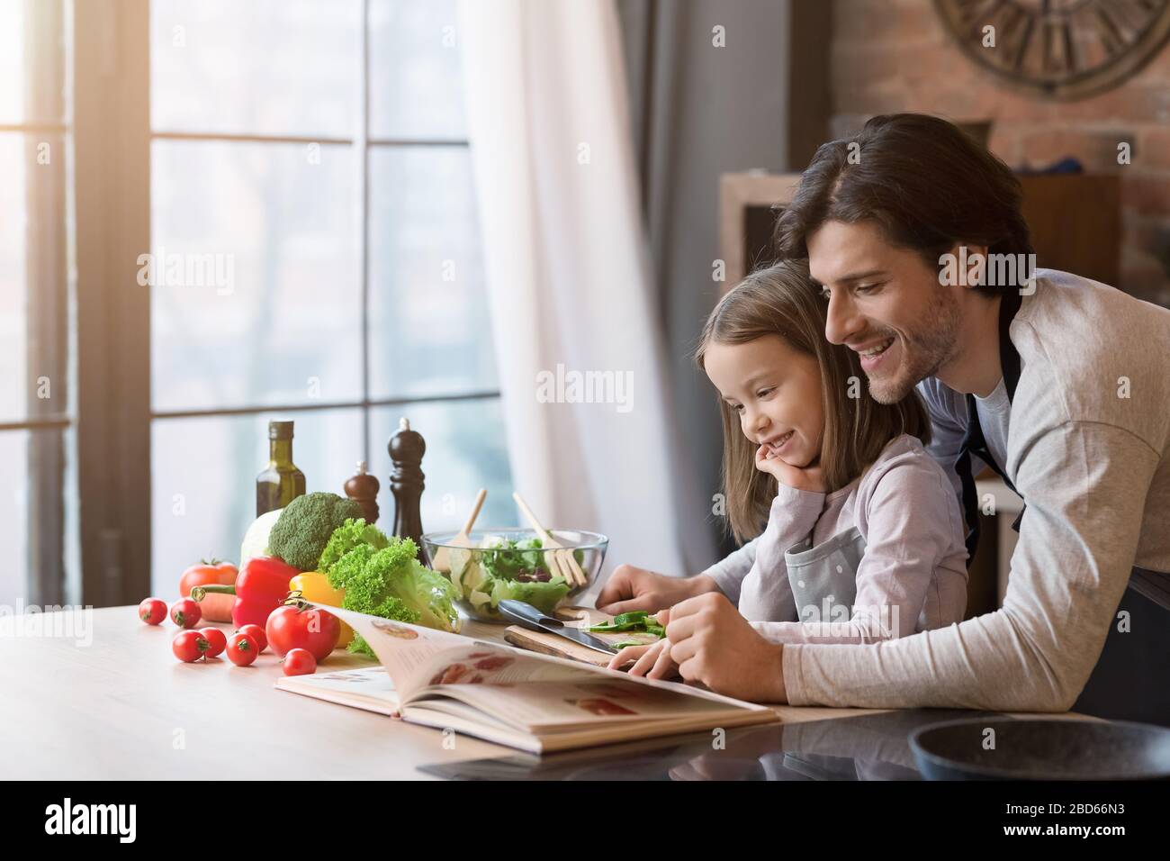 Little girl and father following recipe in culinary book, cooking ...