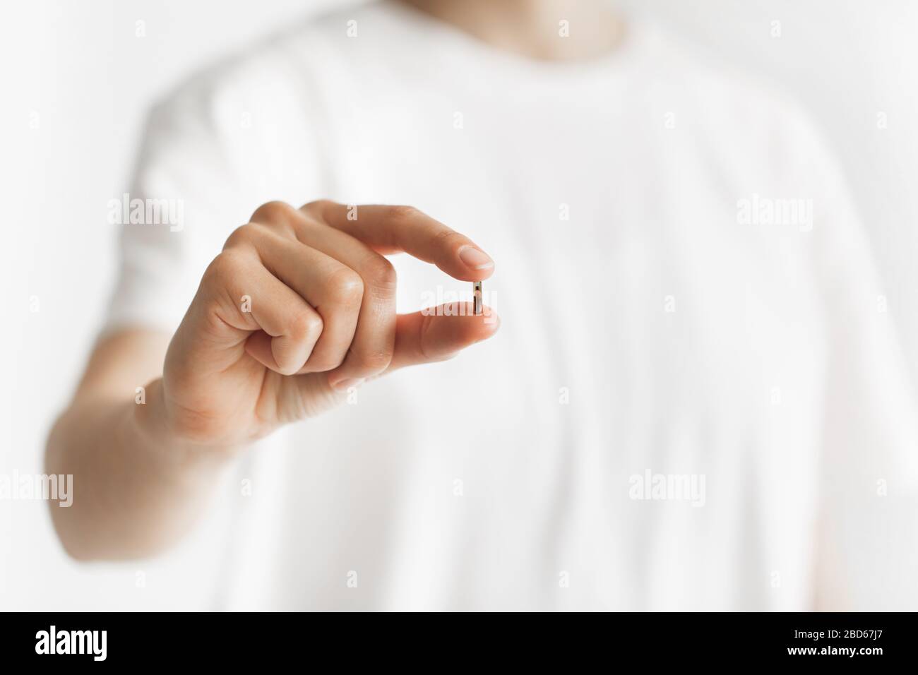 Person holding in fingers micro chip for implantation. Future mandatory ...