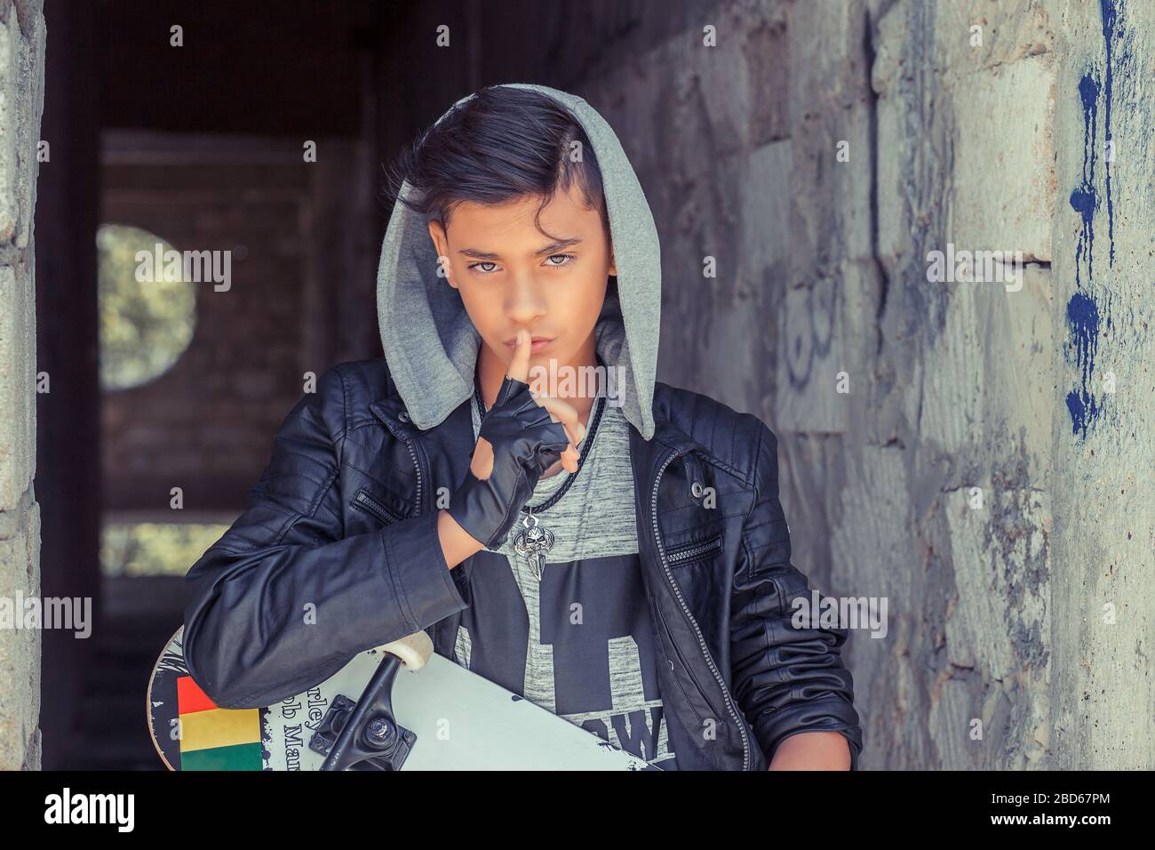 Teenager boy wide eyed asking for silence or secrecy with finger on ...