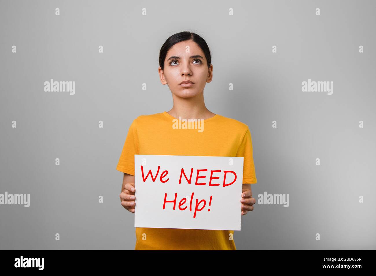 we need help. dramatic portrait of a young woman in yellow t-shirt ...