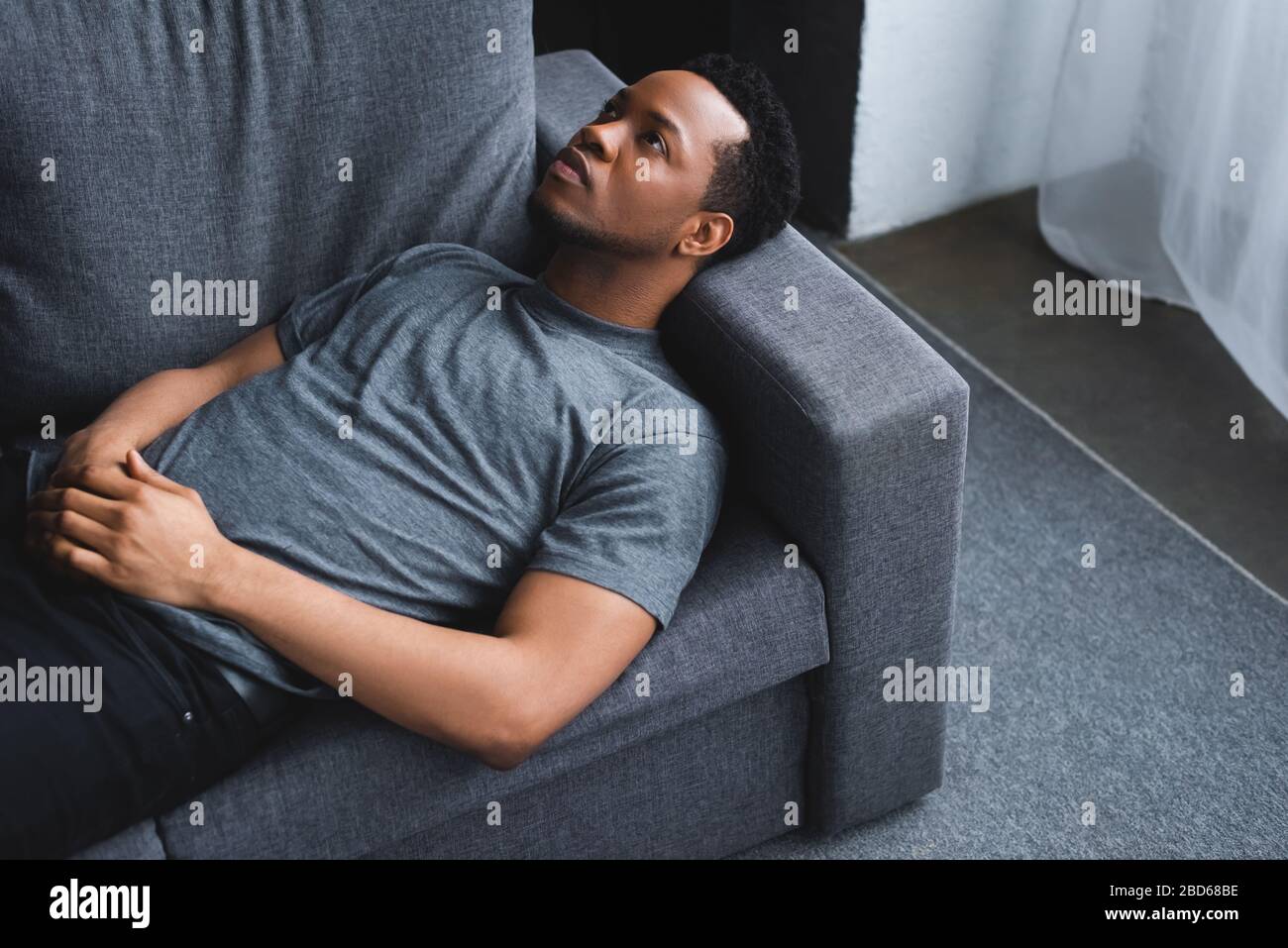 lonely sad african american man lying on sofa at home Stock Photo - Alamy