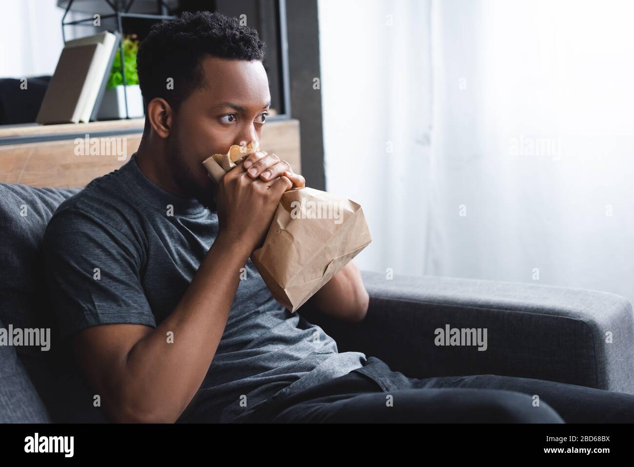 stressed african american man breathing with paper bag while having ...