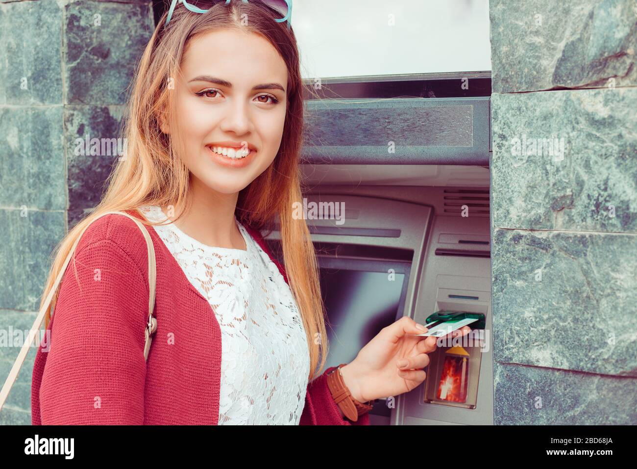 Smiling happy woman puts the card in the ATM,The bank terminal. Modern ...
