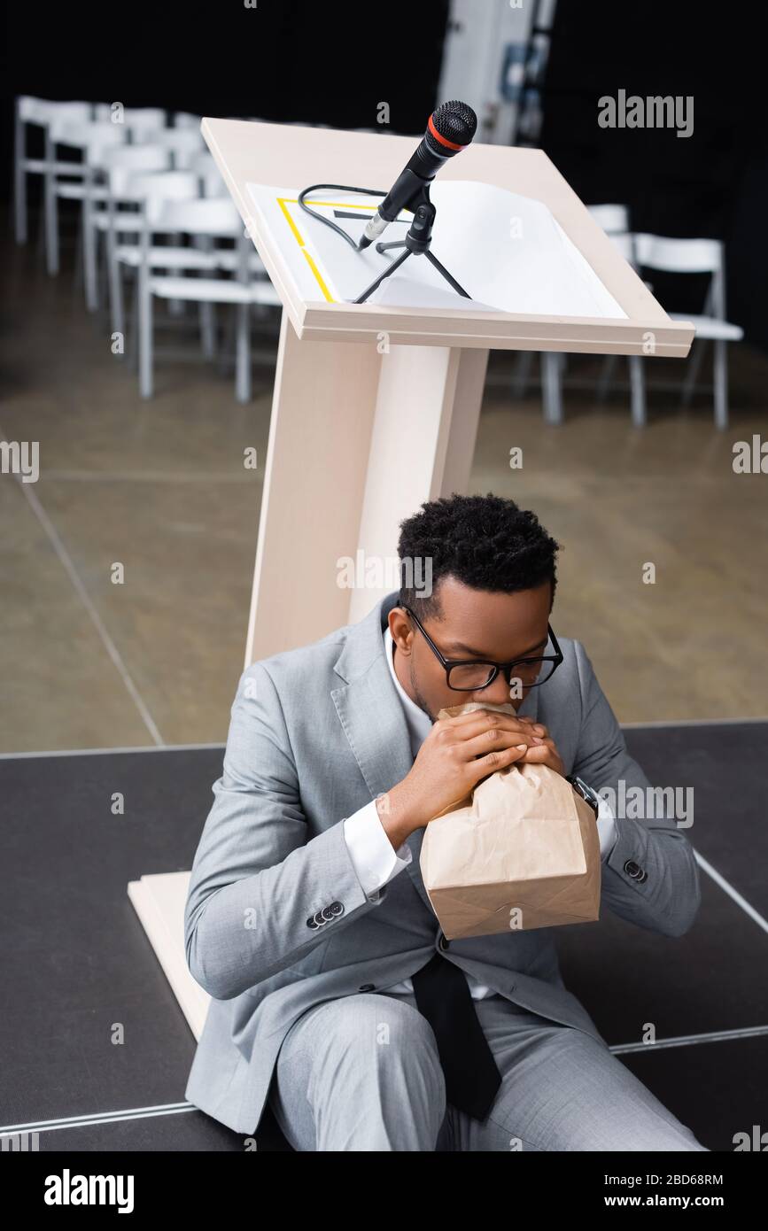 scared african american speaker breathing with paper bag and having ...