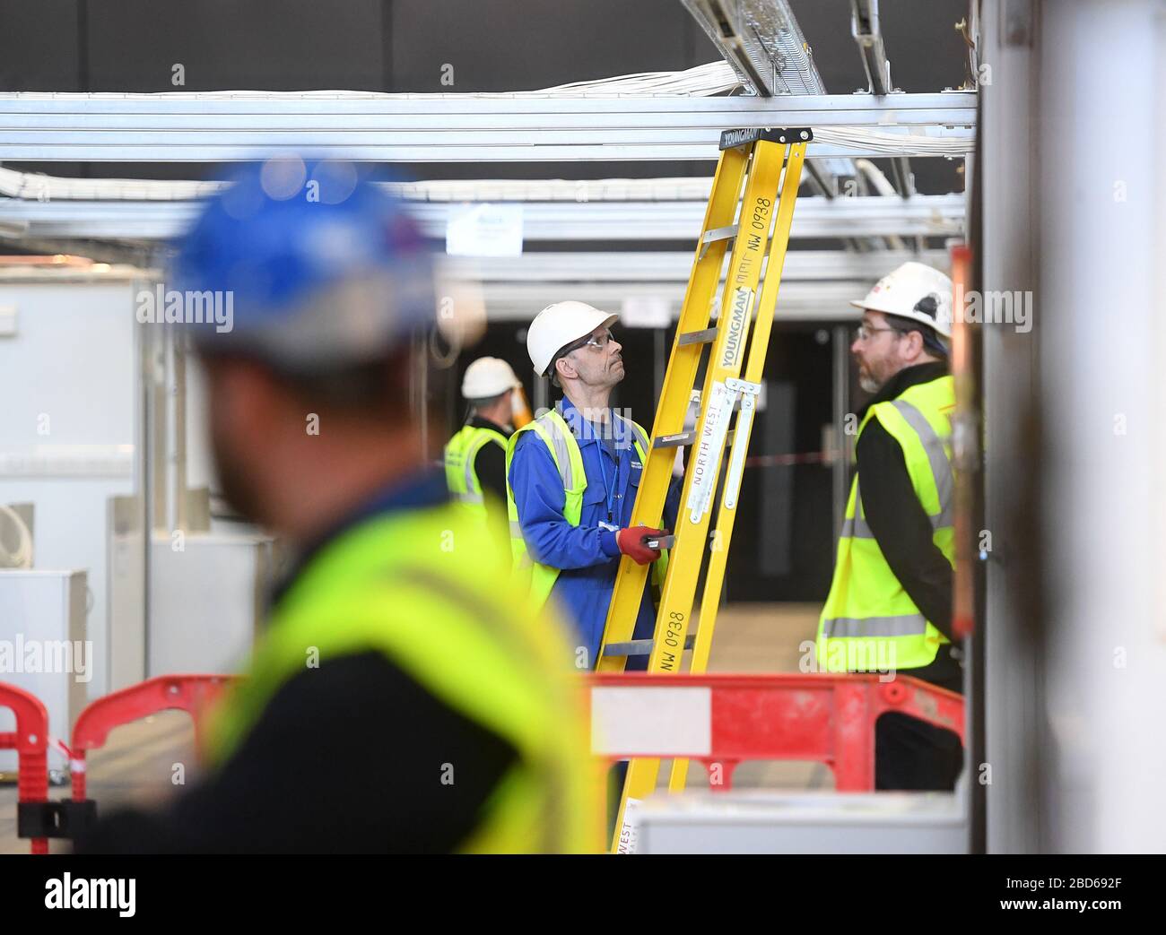 Construction workers at the new temporary NHS Nightingale Hospital ...