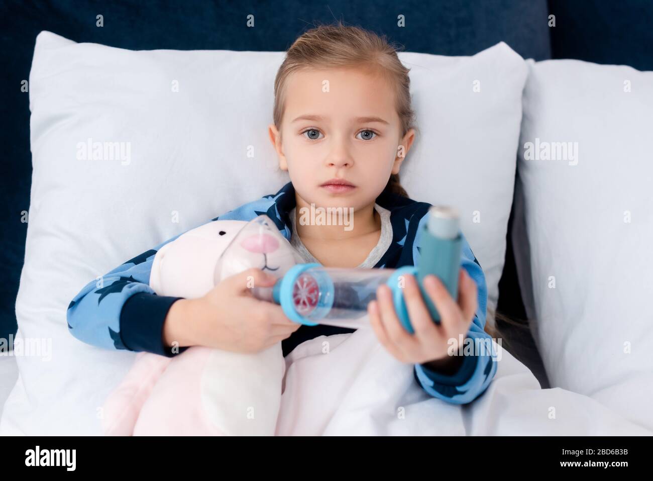 asthmatic kid holding inhaler with spacer near soft toy Stock Photo - Alamy