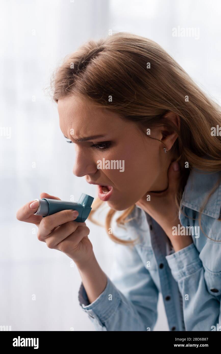 asthmatic woman holding inhaler and touching neck Stock Photo - Alamy