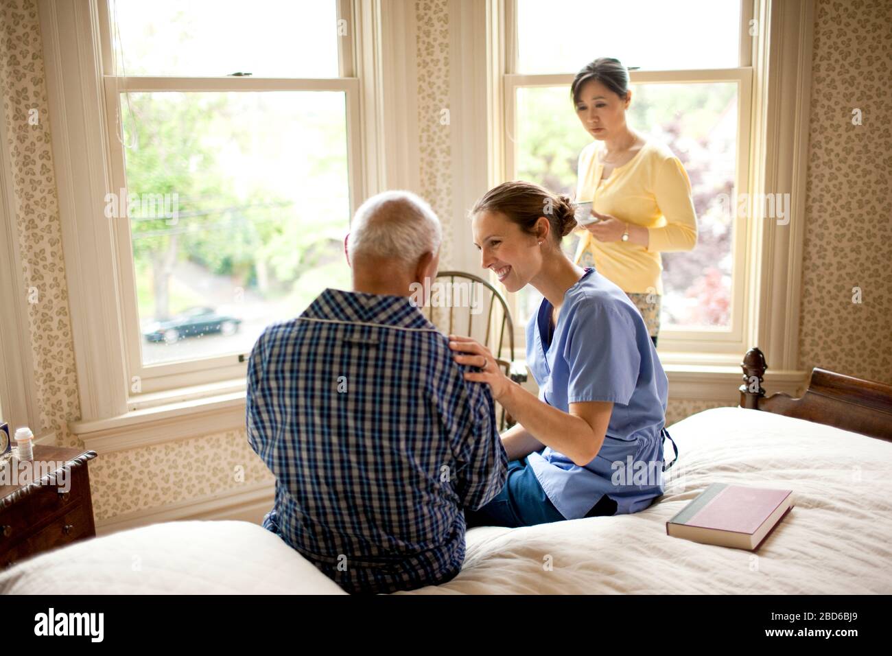 Unwell senior man receiving a visit from his nurse and his adult ...