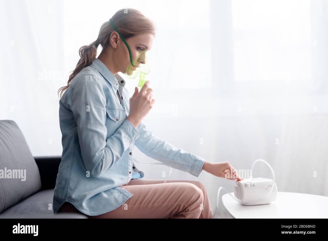 side view of woman in respiratory mask touching compressor inhaler ...