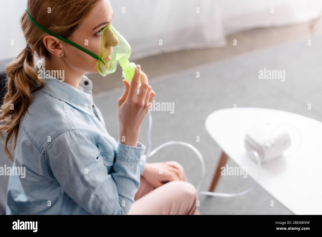 selective focus of asthmatic woman in respiratory mask using compressor ...