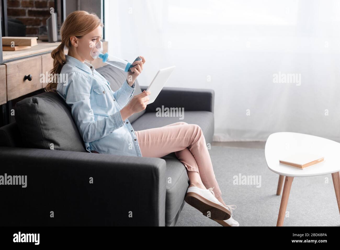 side view of asthmatic woman using inhaler with spacer and holding ...