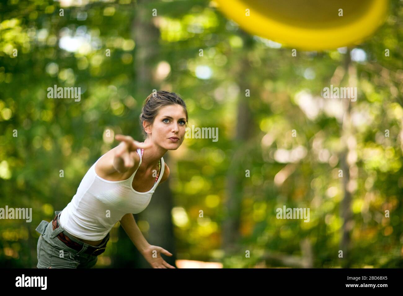 Woman throwing a frisbee in a forest Stock Photo - Alamy
