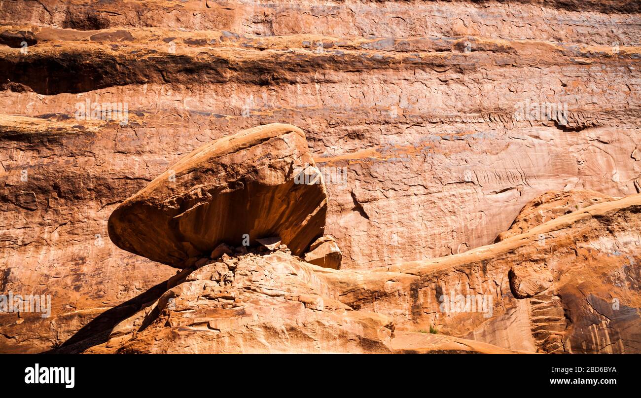 Larg sandstone boulder below a vertical stone wall in Arches National ...