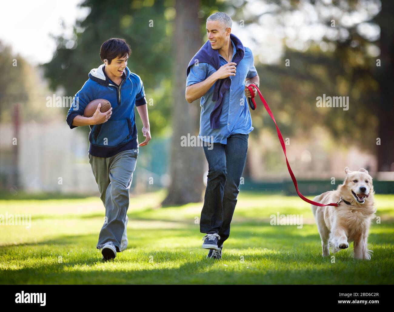 Smiling mid adult man and his son having fun jogging together in the ...