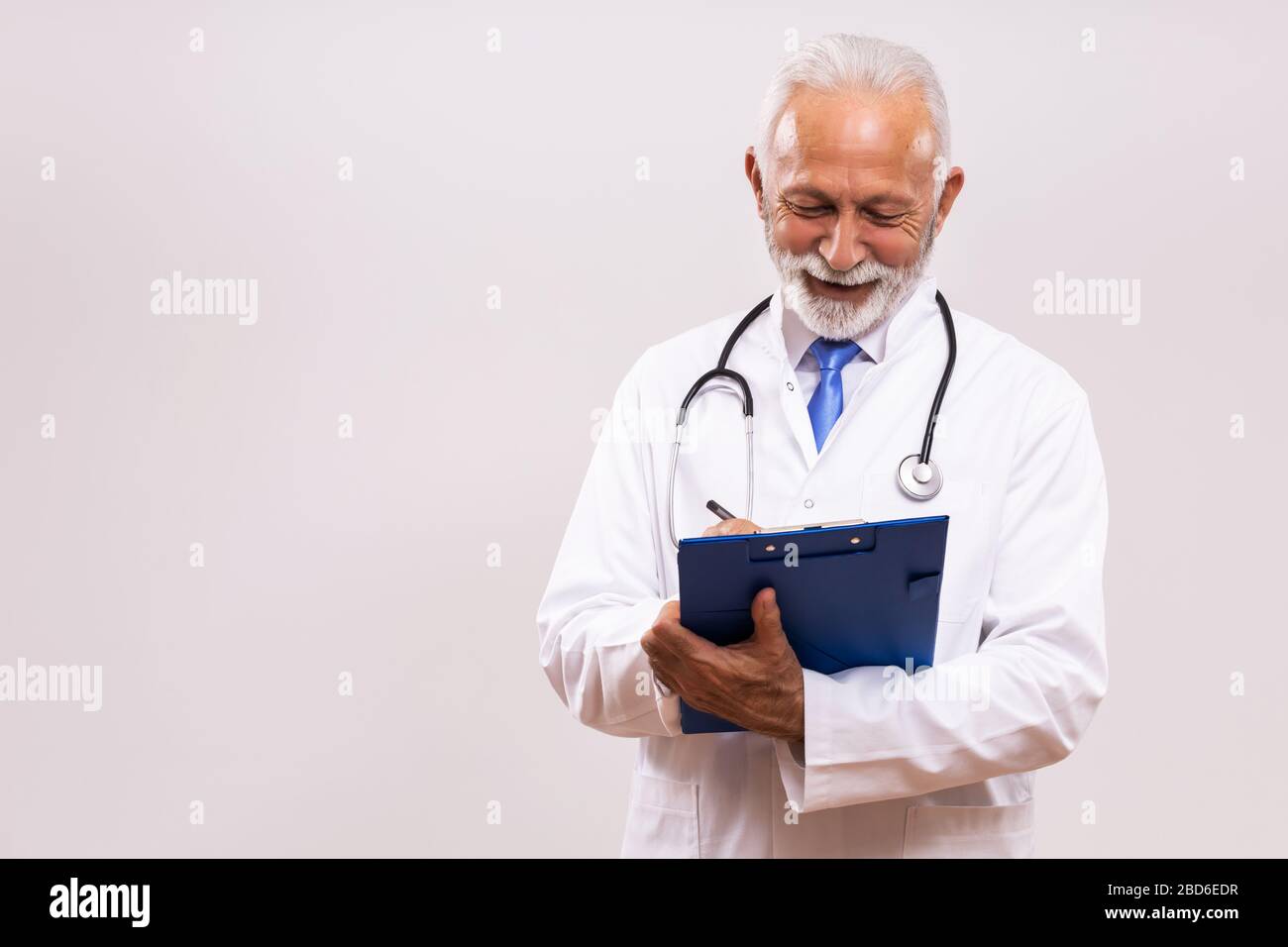 Portrait of senior doctor writing notes on gray background Stock Photo ...