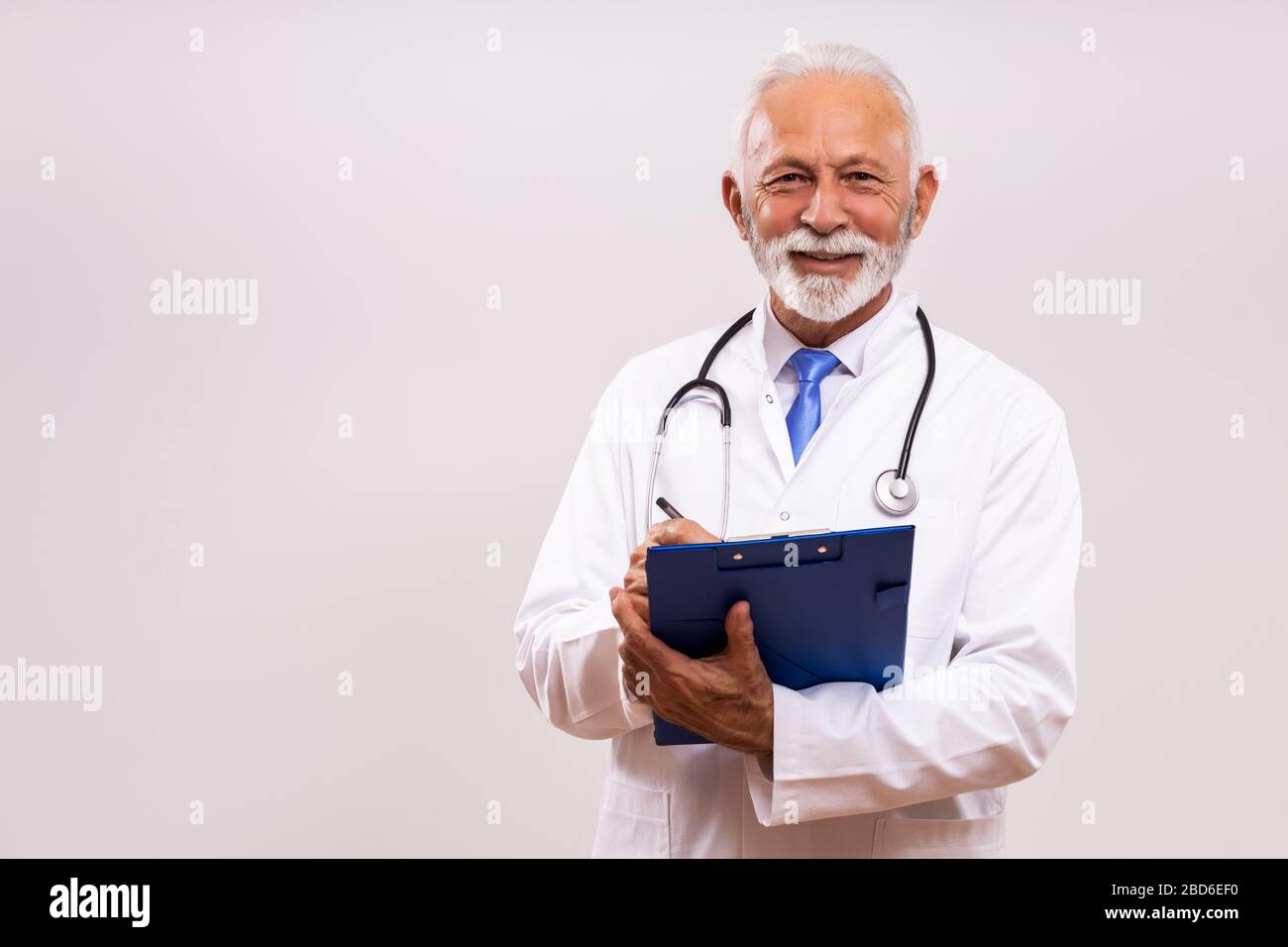 Portrait of senior doctor writing notes on gray background Stock Photo ...