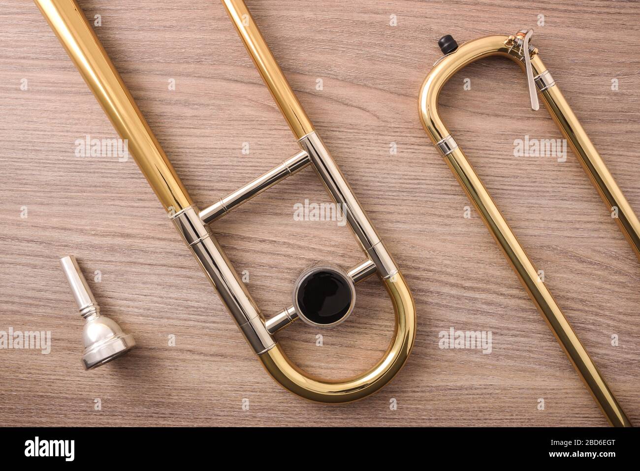 Golden slide trombone disassembled on wooden table. Top view ...