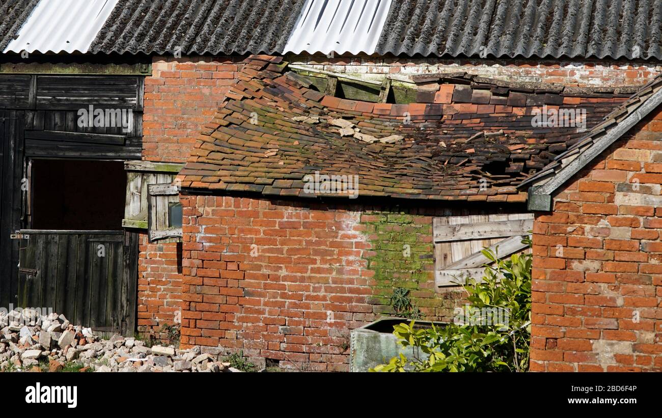 A derelict farm building and barn with a collapsing tile roof Stock ...