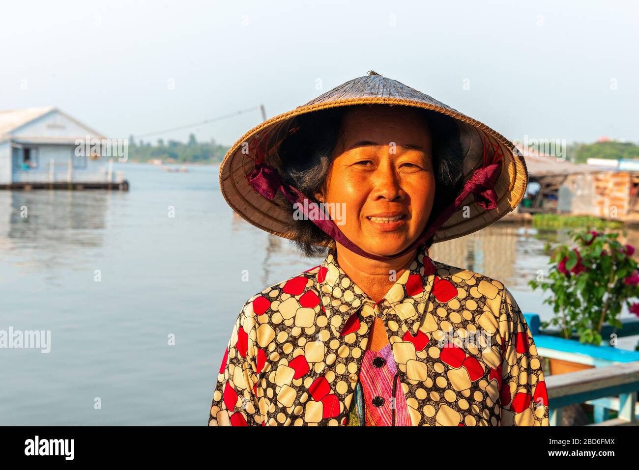 Smiling Vietnamese woman living on a floating house and wearing a ...
