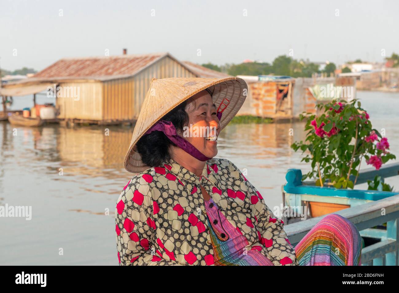 Smiling Vietnamese woman living on a floating house and wearing a ...