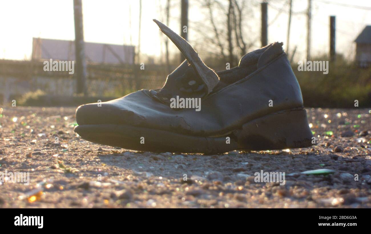 An old boot in the midst of urban trash, lie on the pavement under the ...