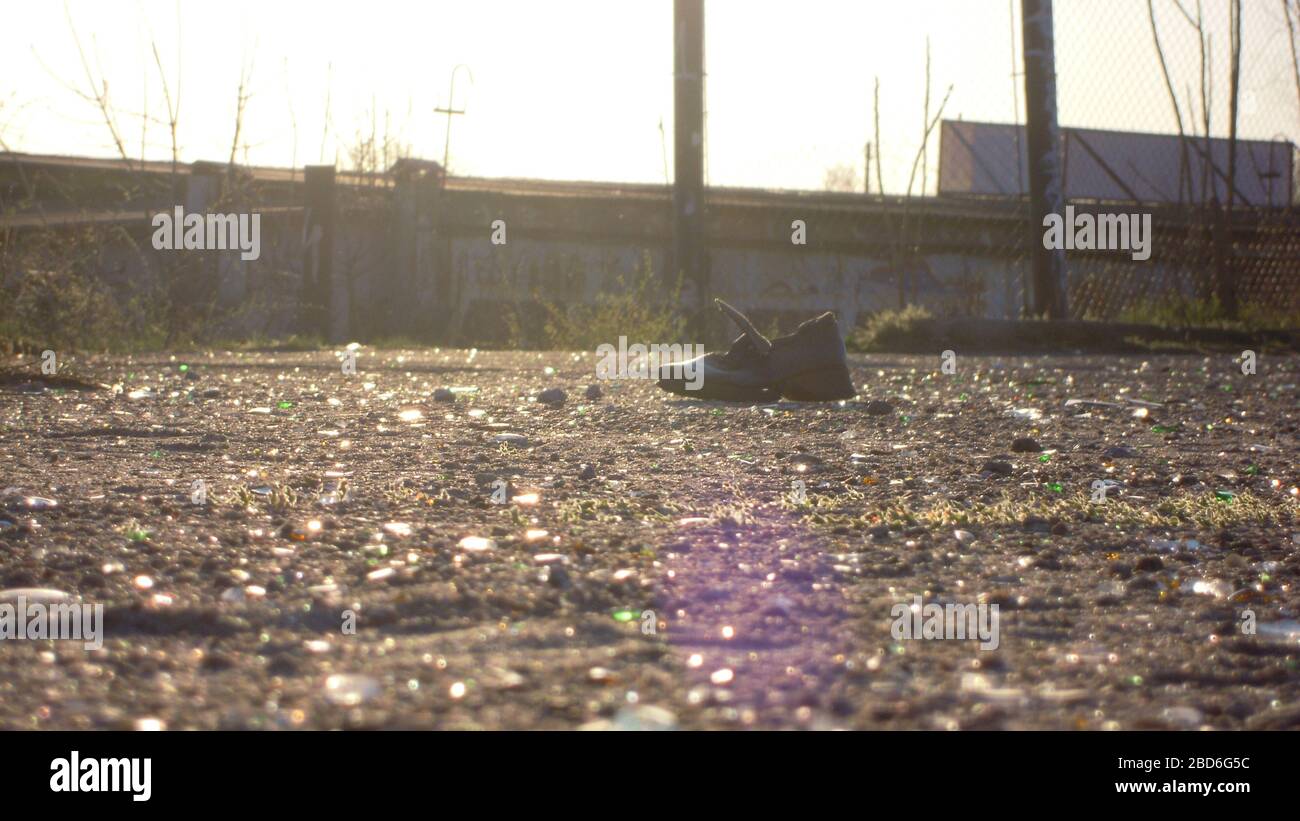 An old boot in the midst of urban trash, lie on the pavement under the ...