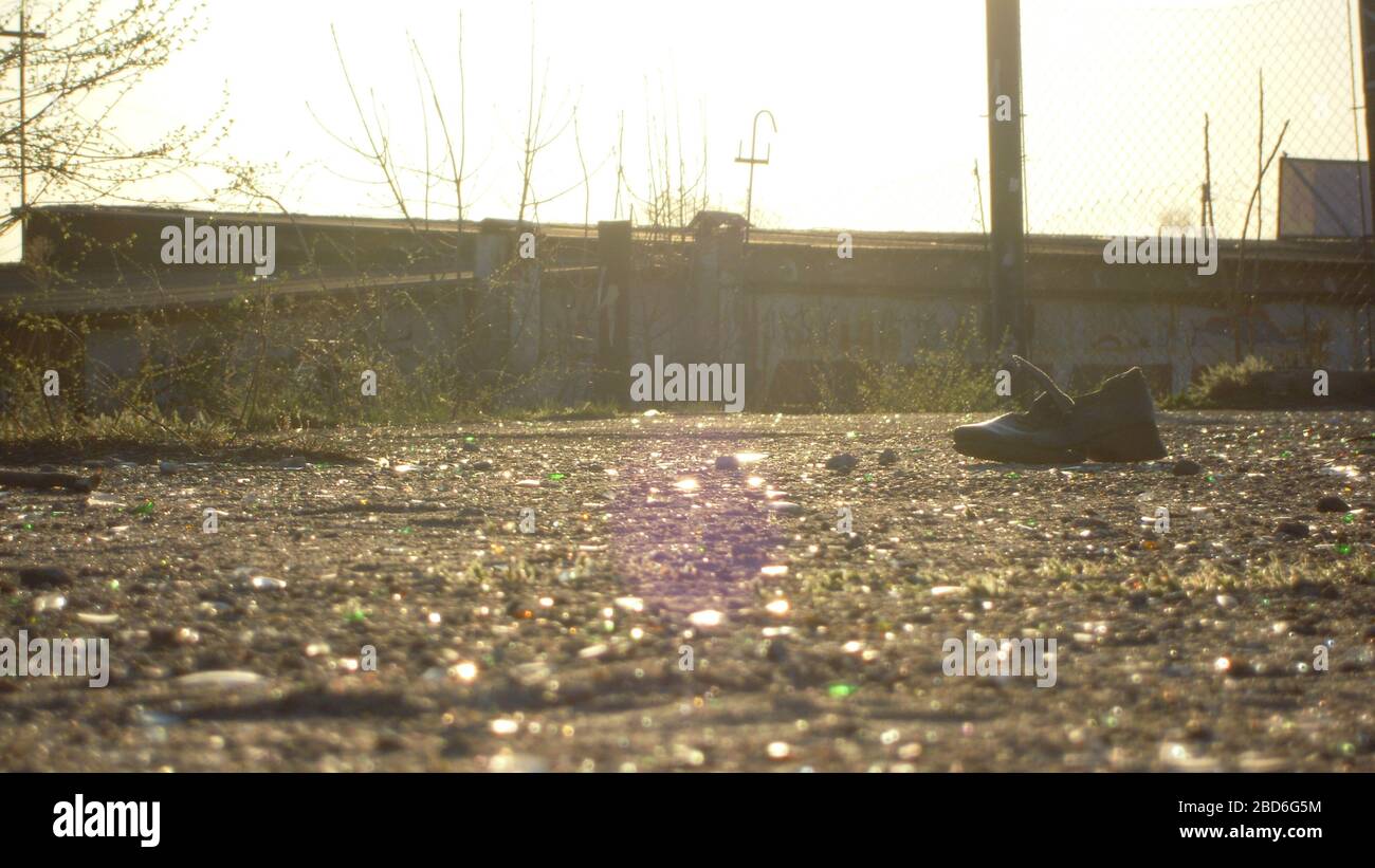 An old boot in the midst of urban trash, lie on the pavement under the ...