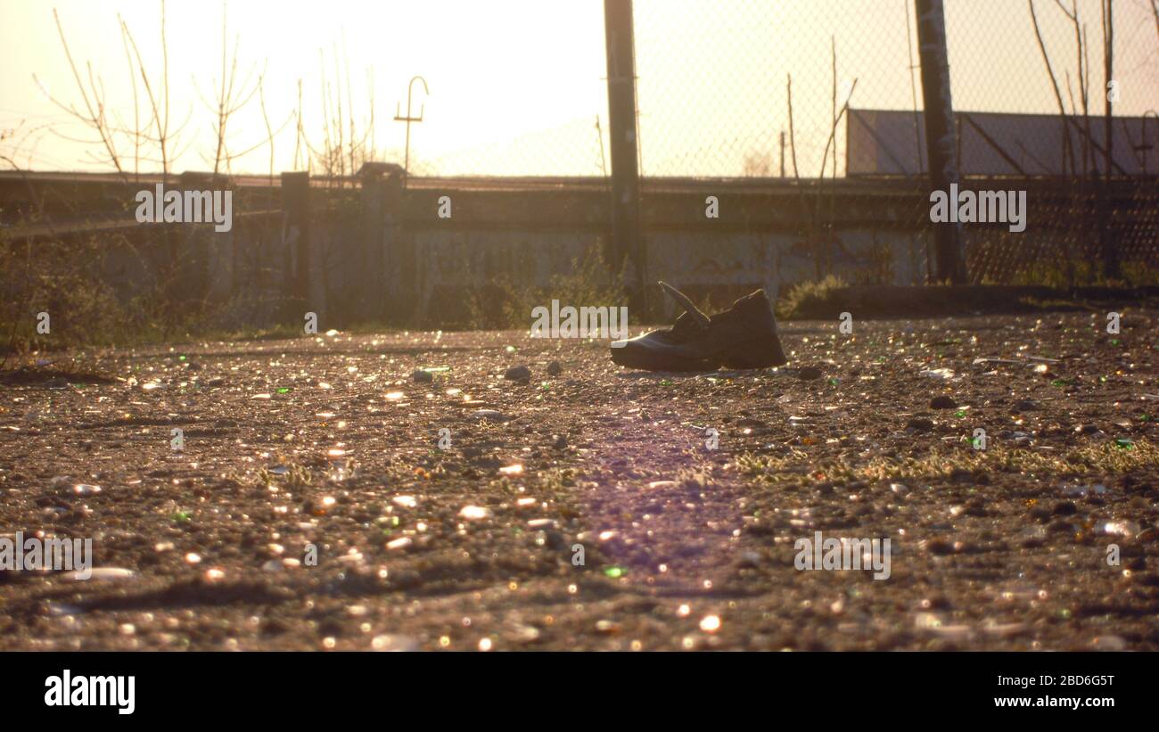 An old boot in the midst of urban trash, lie on the pavement under the ...