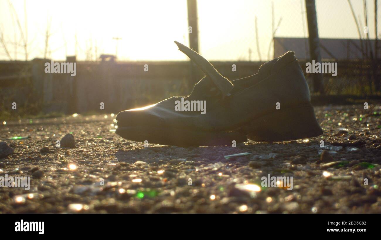 An old boot in the midst of urban trash, lie on the pavement under the ...