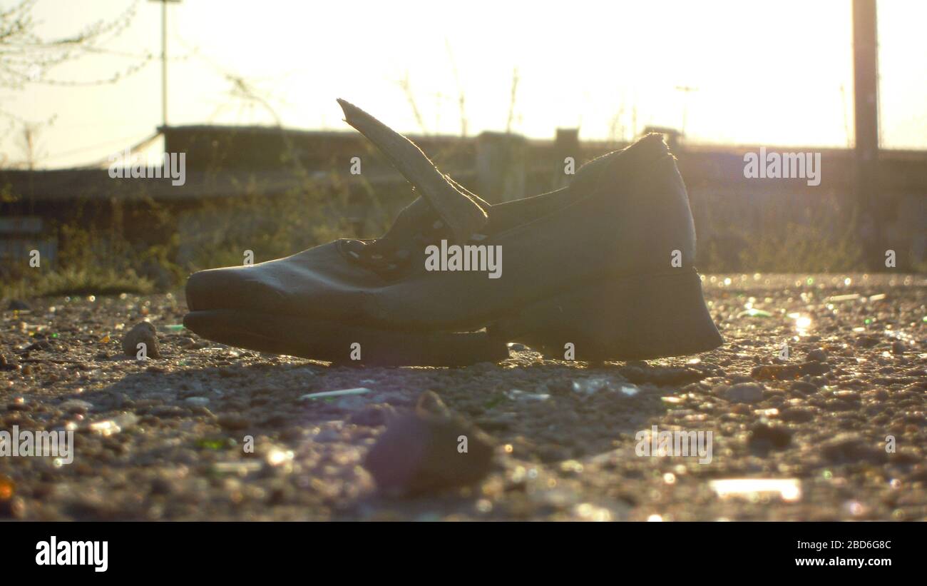 An old boot in the midst of urban trash, lie on the pavement under the ...