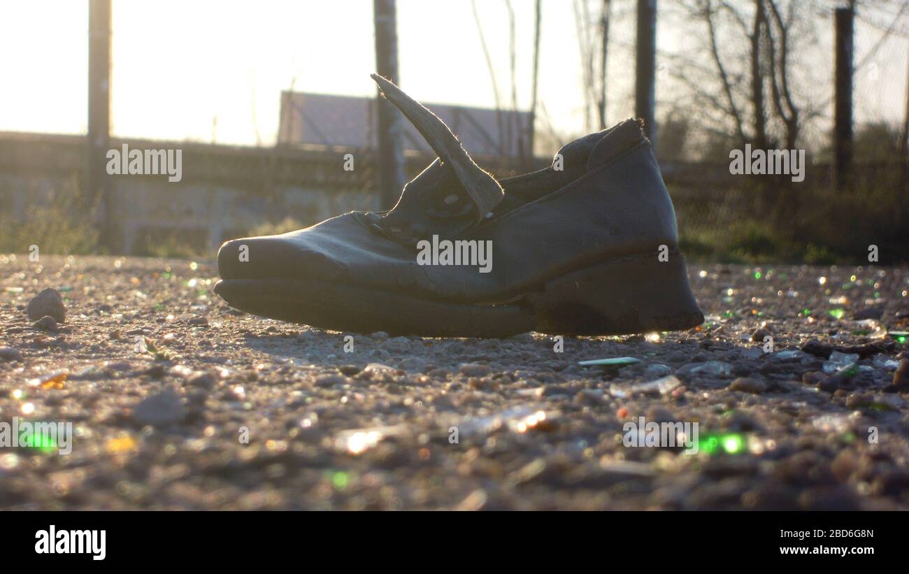 An old boot in the midst of urban trash, lie on the pavement under the ...