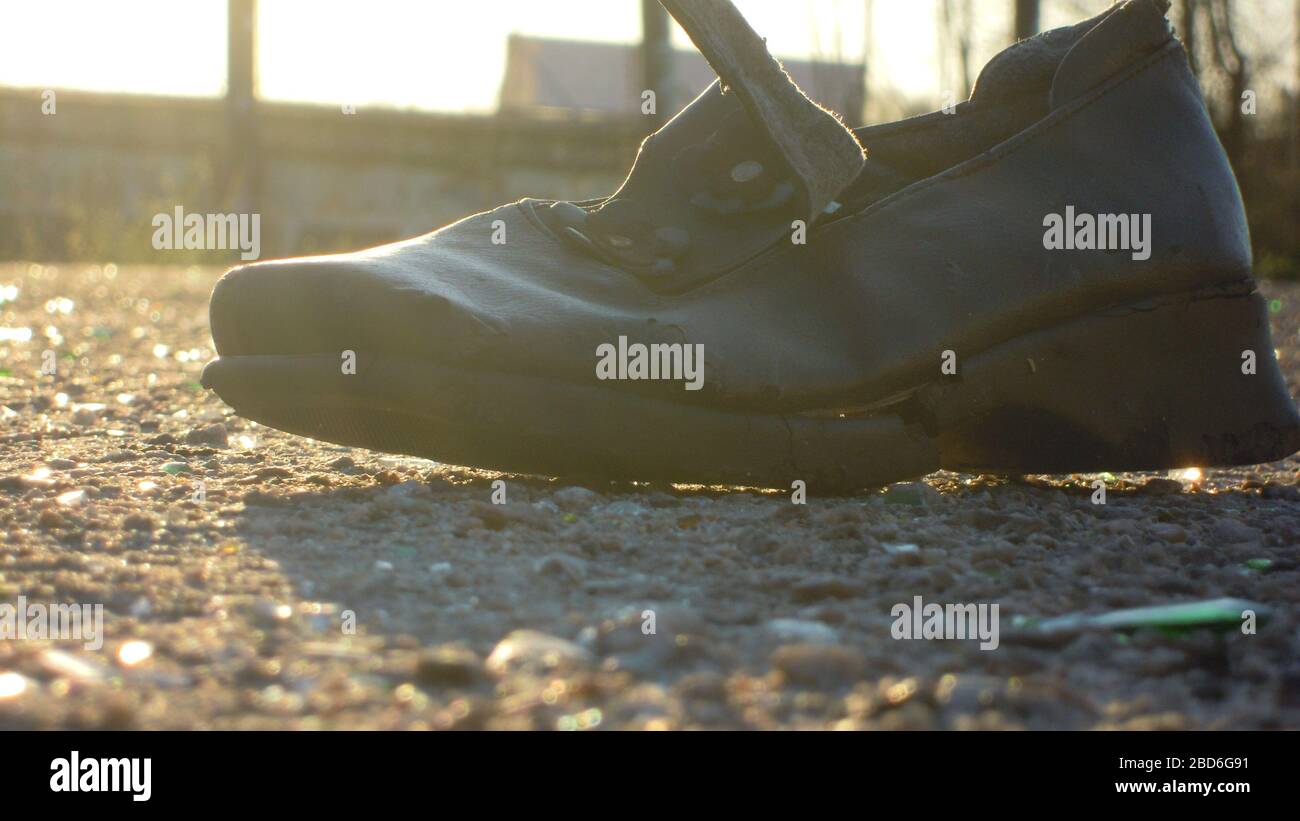 An old boot in the midst of urban trash, lie on the pavement under the ...