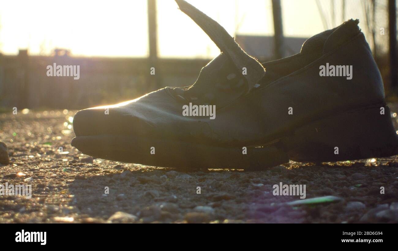 An old boot in the midst of urban trash, lie on the pavement under the ...