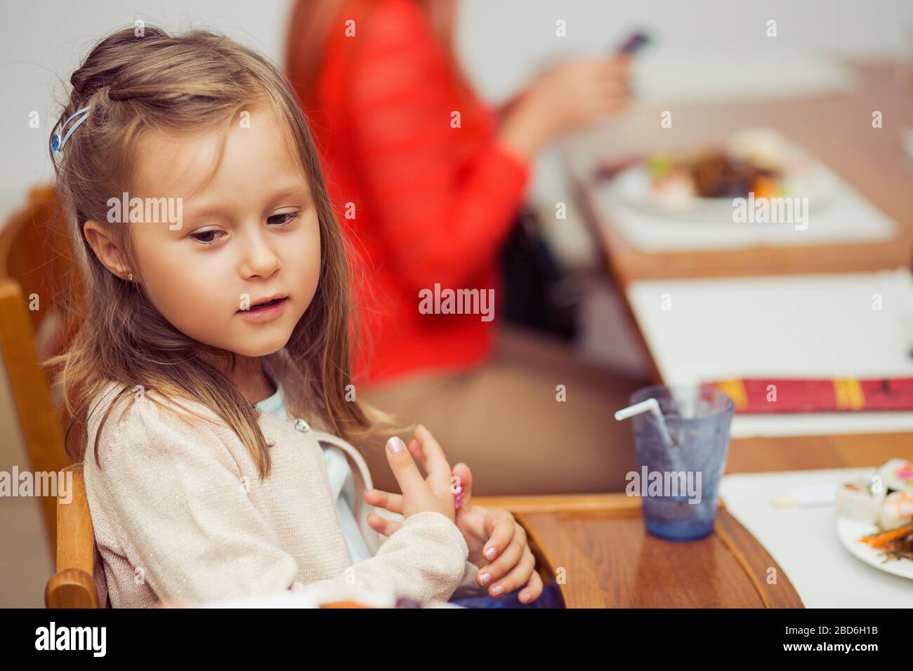 Kid in restaurant. Spoiled child in restaurant in front of plate with ...