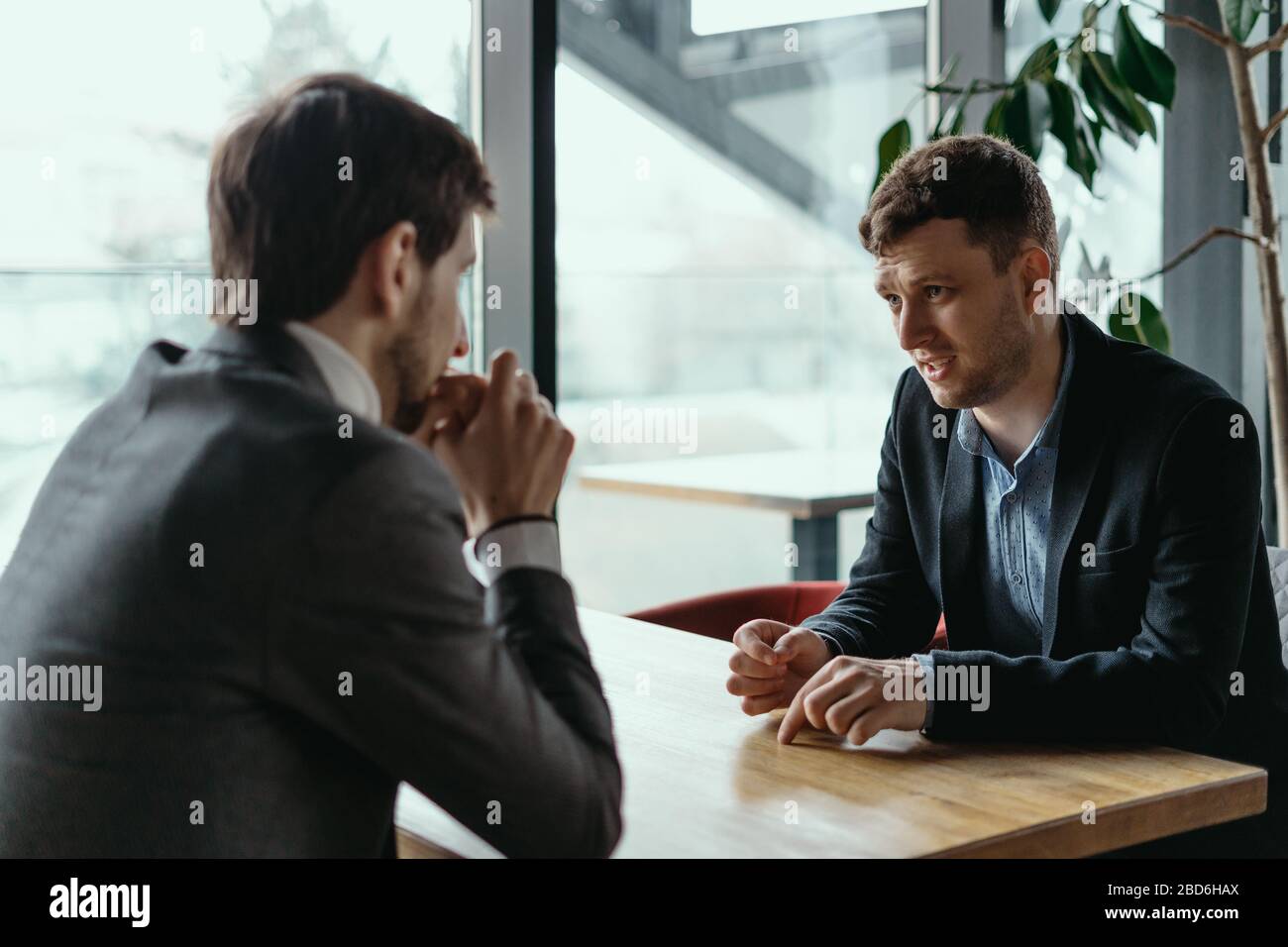 Focused businessman listening to business partner talking during ...